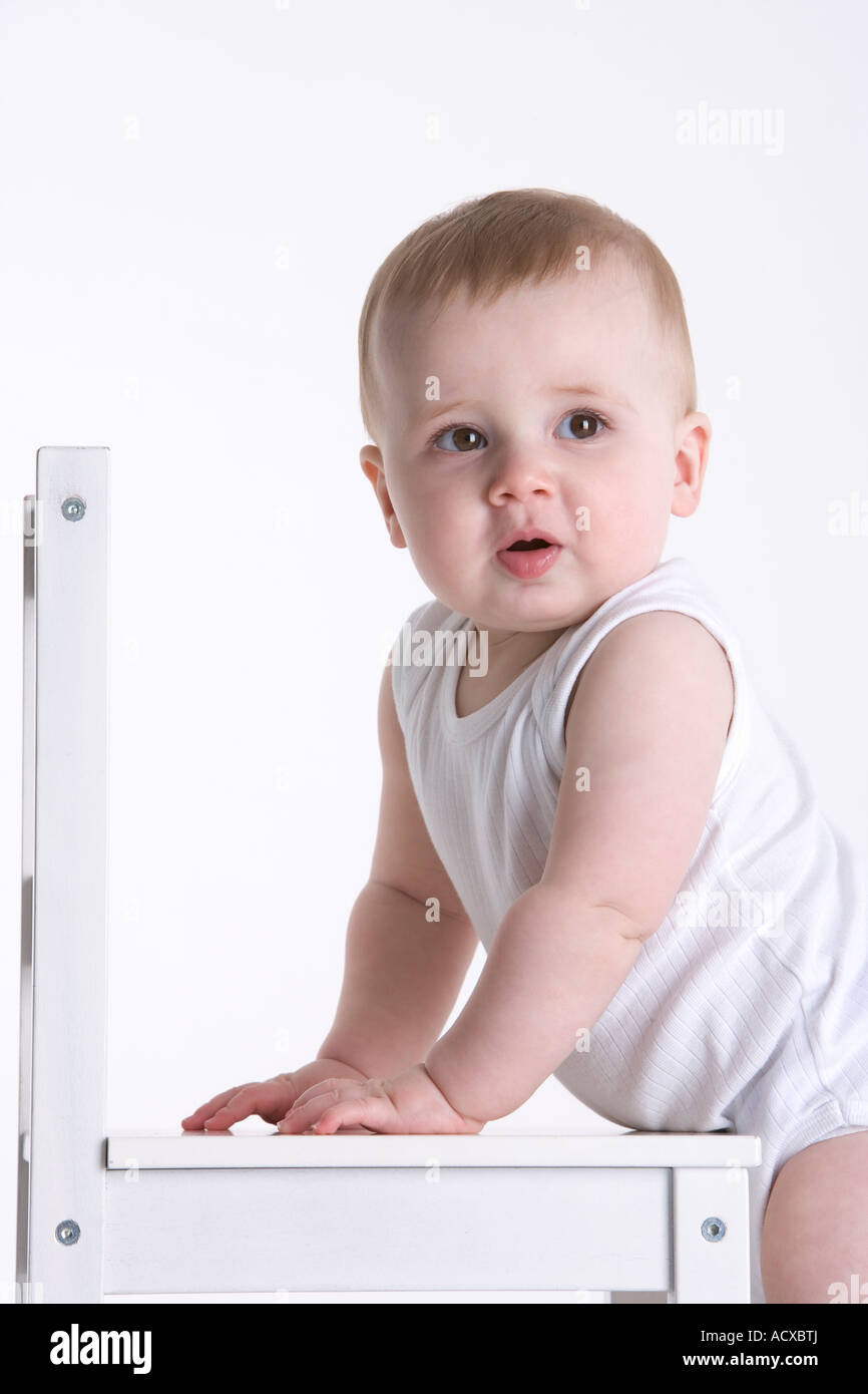 Baby boy standing against a little chair Stock Photo - Alamy