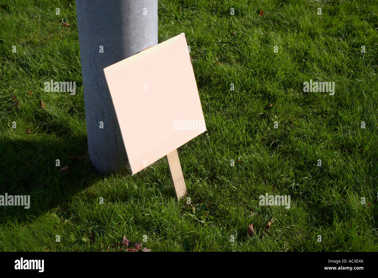 Empty demonstration placard leaning to a metal post on a green grassy ...