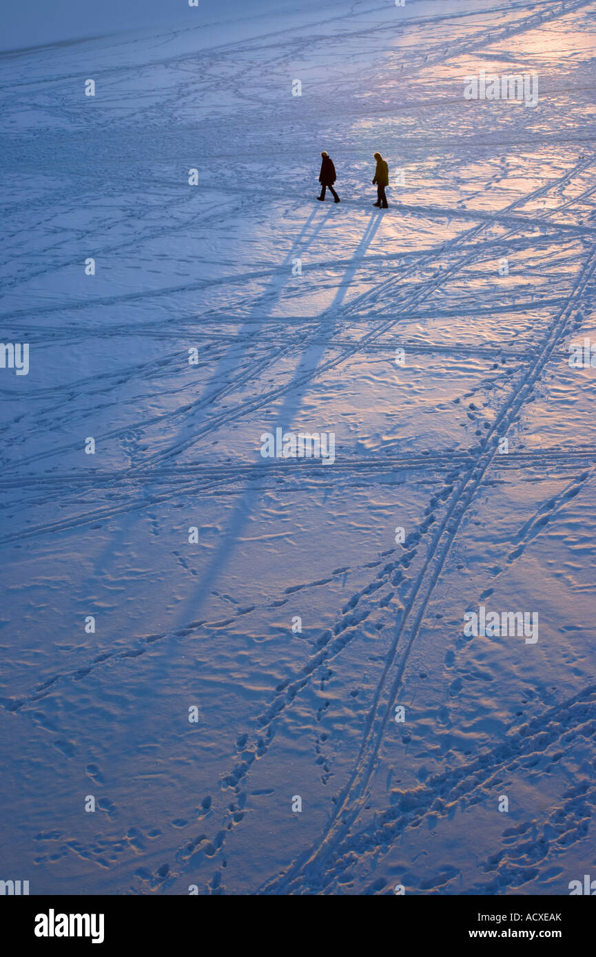 Two people walking through snow on frozen sea at Helsinki, Finland, EU ...