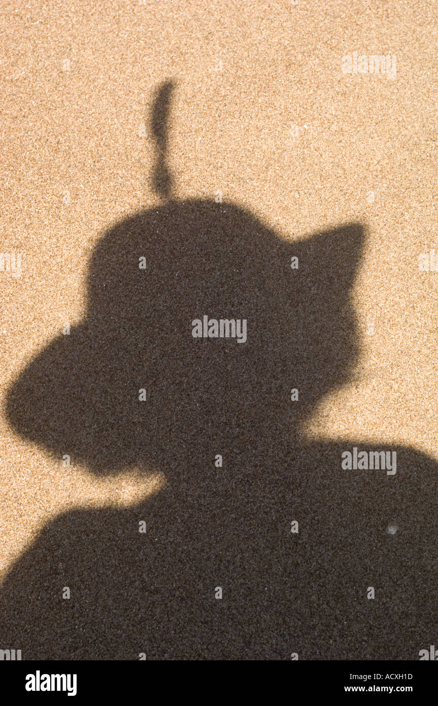 Shadow of the head and shoulders of a person in a broad brimmed hat ...