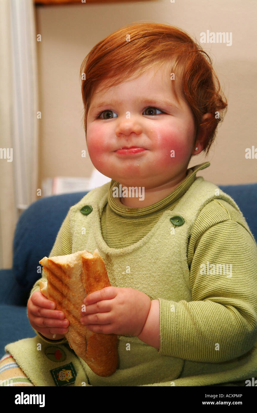 Little baby girl with a piece of bread Stock Photo - Alamy