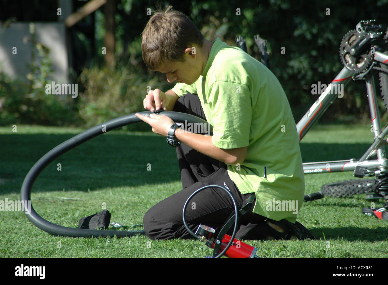 Teenage Boy Engrossed in Mending a Bike Puncture in the Garden Stock ...