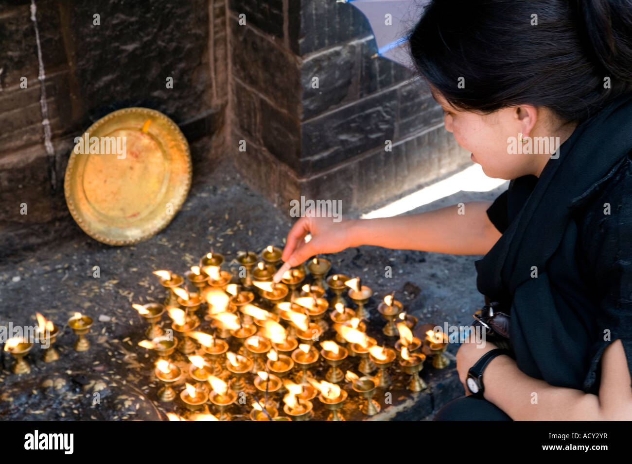 Nepali woman lighting offering butter lamps.Swayambhunath Stupa ...