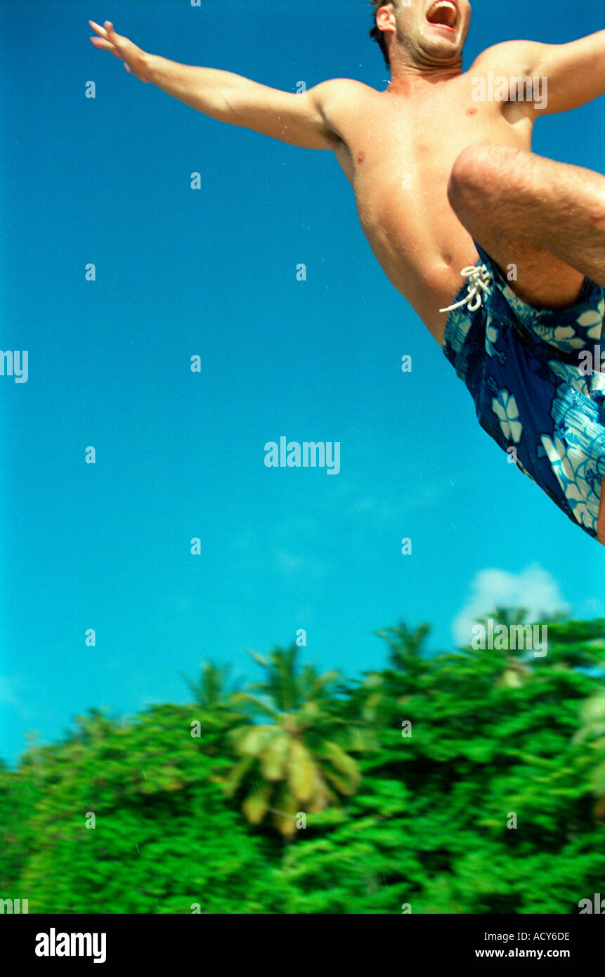 young man in blue trunks jumping on tropical beach Stock Photo - Alamy