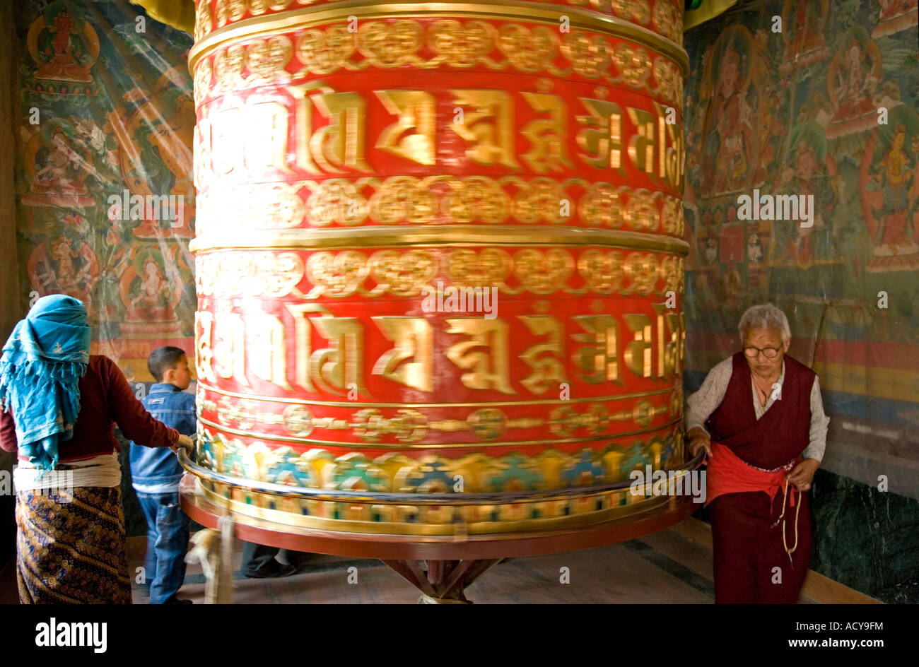 Tibetan pilgrims spinning a big prayer wheel.Tsamchen Gompa.Bodhnath ...