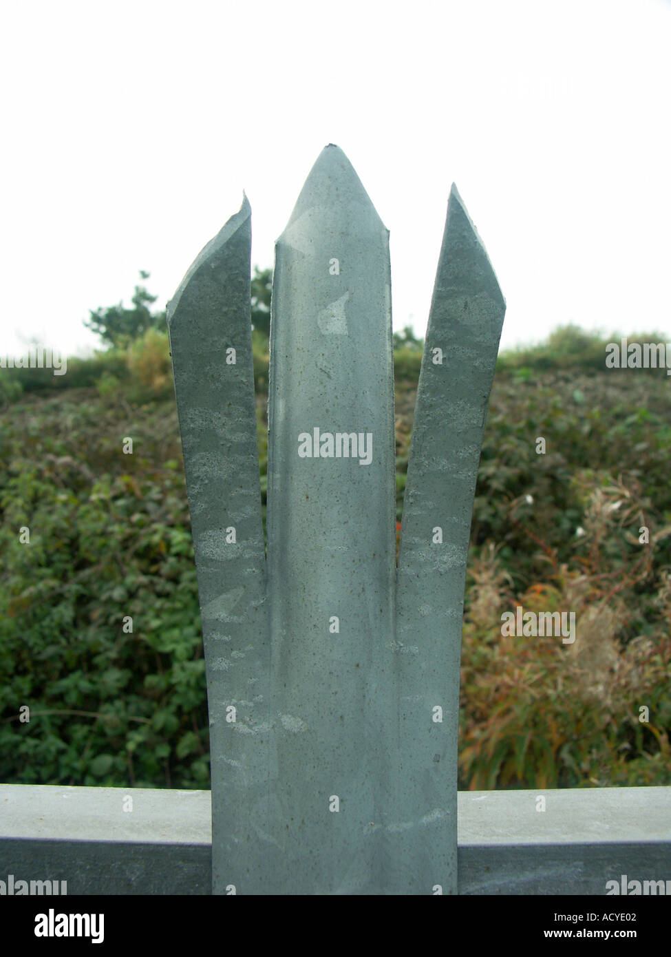 Sharp curved spikes on the top of a security fence along the side of a ...