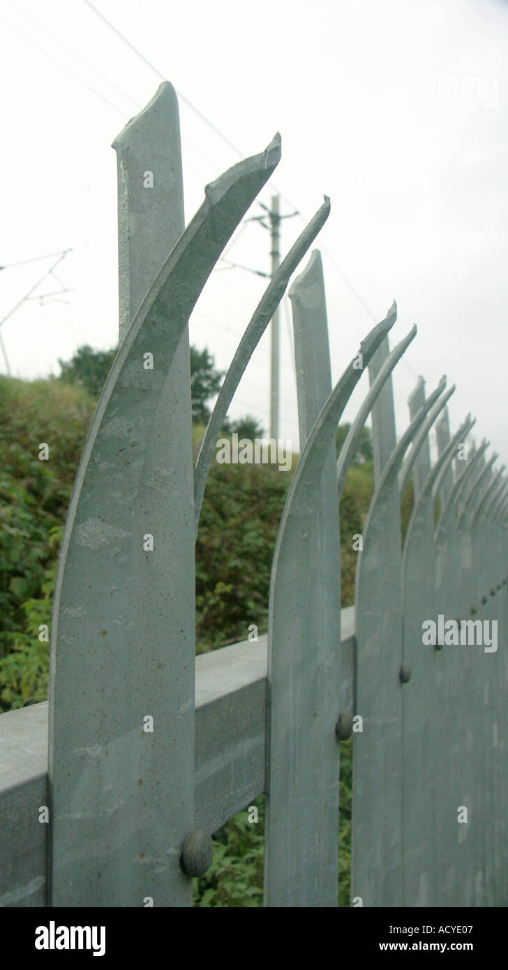 Sharp curved spikes on the top of a security fence along the side of a ...