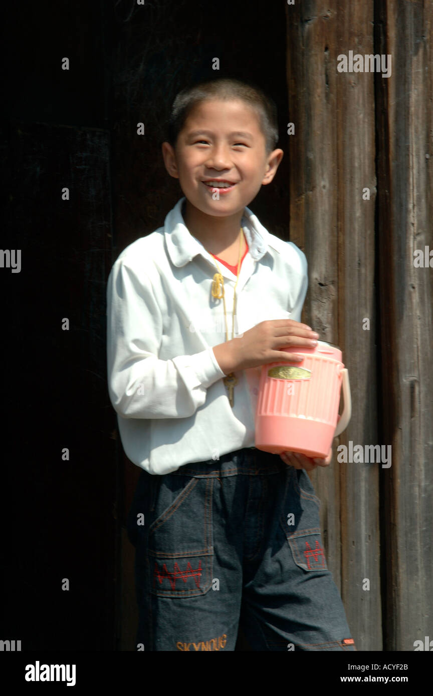 Young smiling Chinese boy wearing a white shirt and red vest coming out ...
