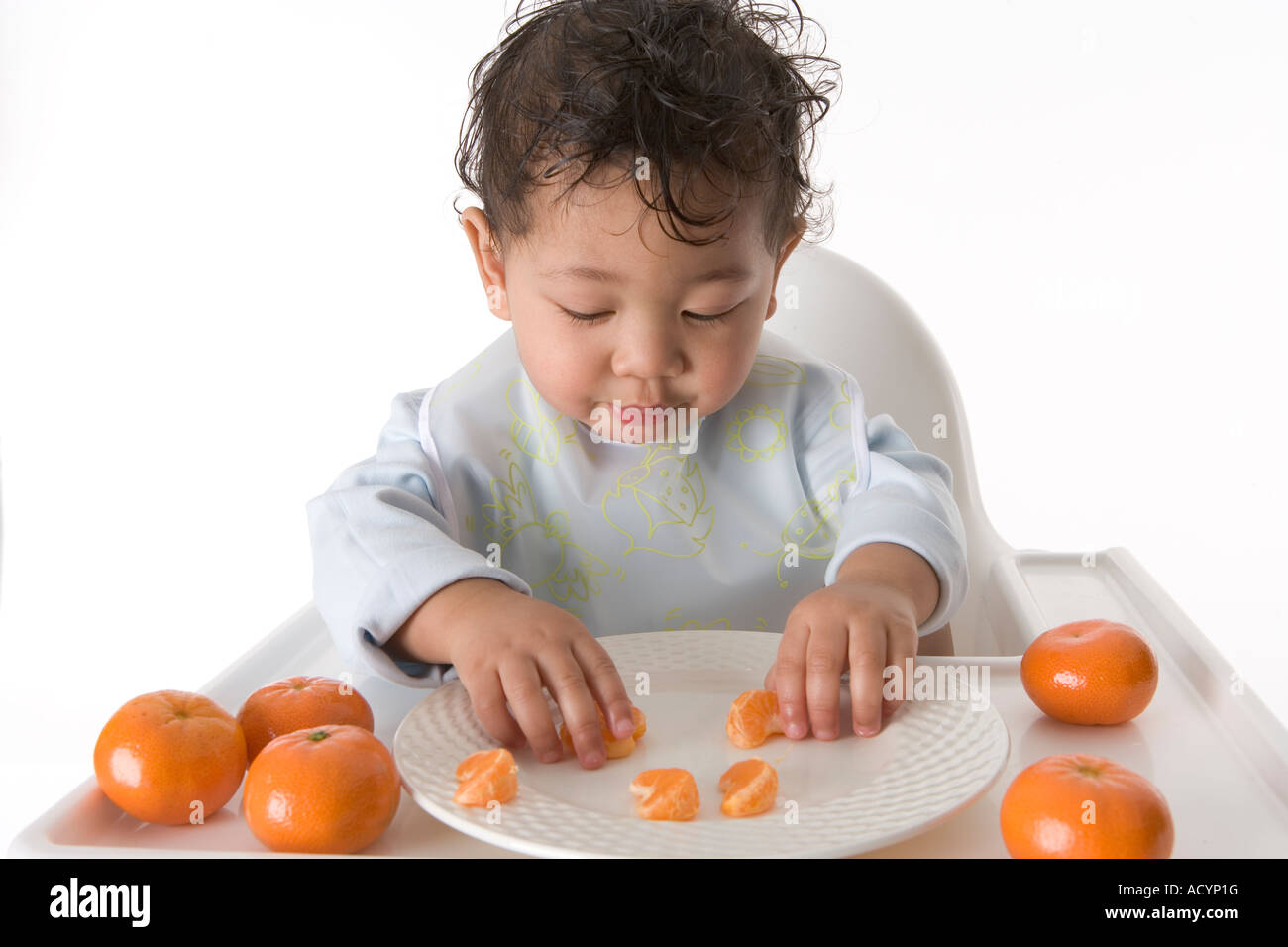 Little toddler boy eating a mandarin Stock Photo - Alamy