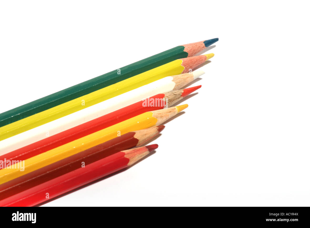 A row of sharpened colored pencils in red, yellow, green, and white arranged diagonally on a ...