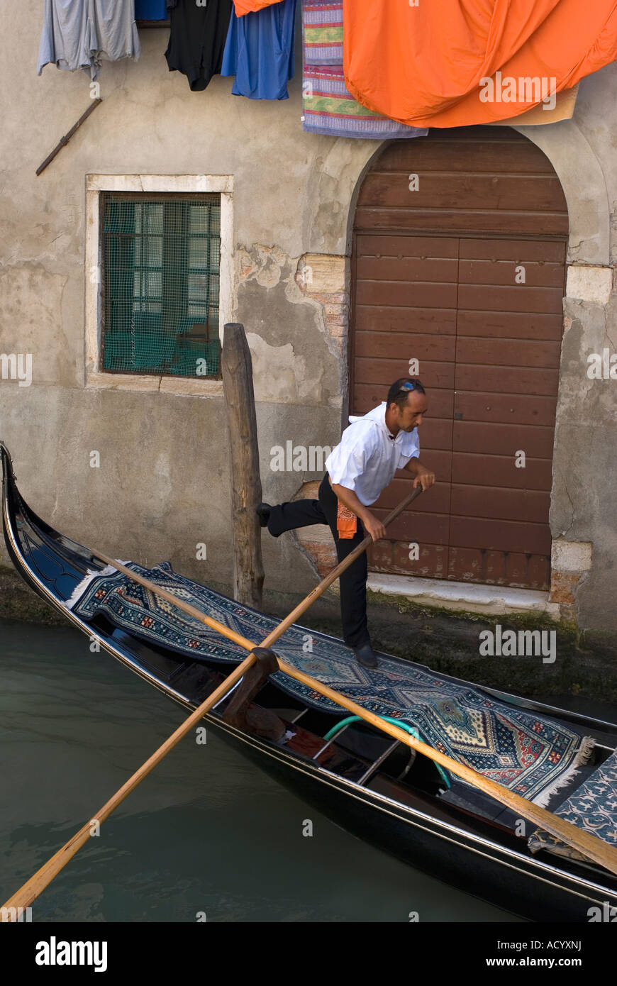 A gondola and its boatman in the canals of Venice in front of an old ...