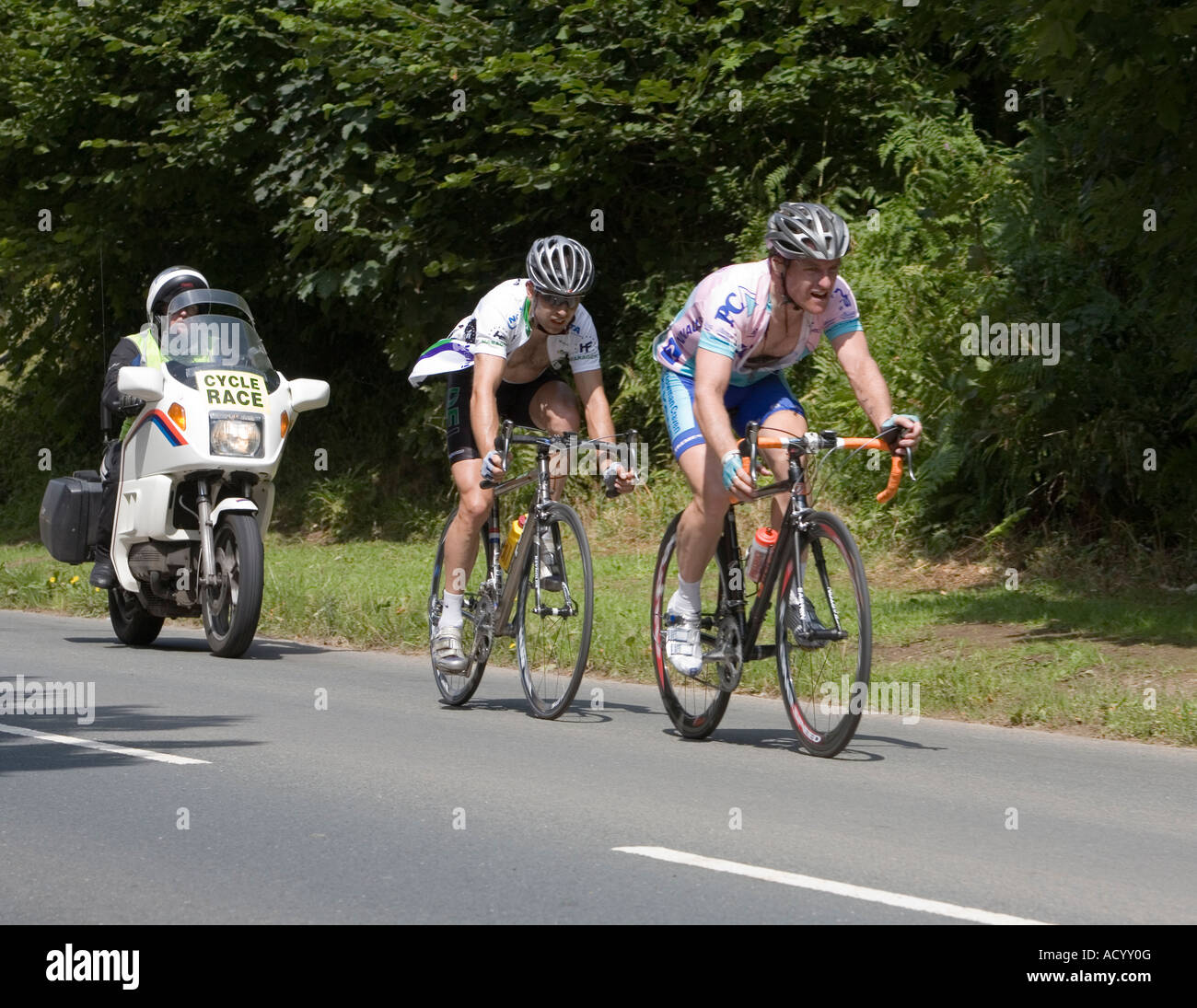 Two cyclists in cycling road race followed by safety motorbike Wales UK ...