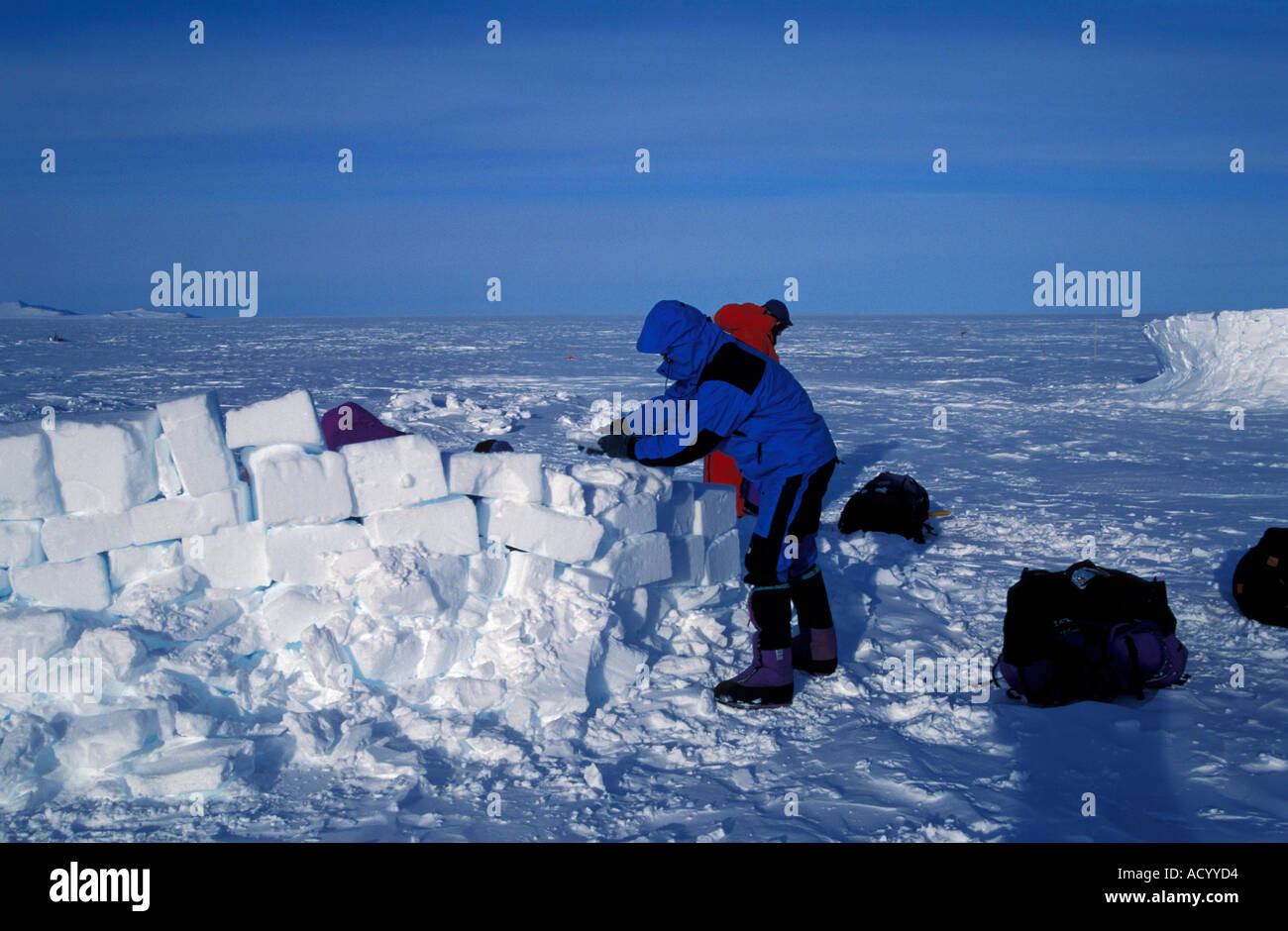 Explorers building a wind shelter by ice blocks Stock Photo - Alamy
