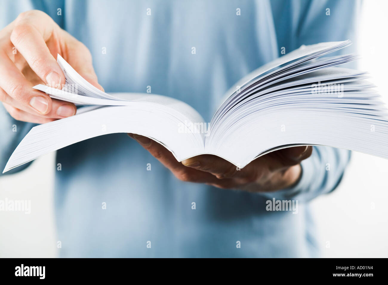 man wearing blue jumper holding book turning pages Stock Photo - Alamy