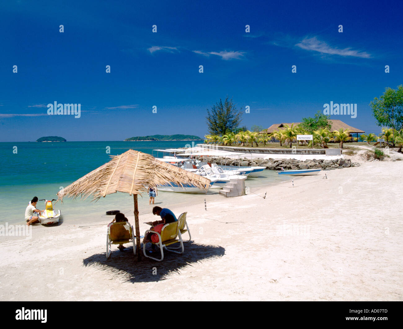 beach with white sand and two people under a rush/vegetation made ...