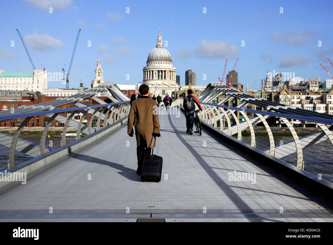 People walk over the Millenium Bridge towards St Pauls Cathedral London ...