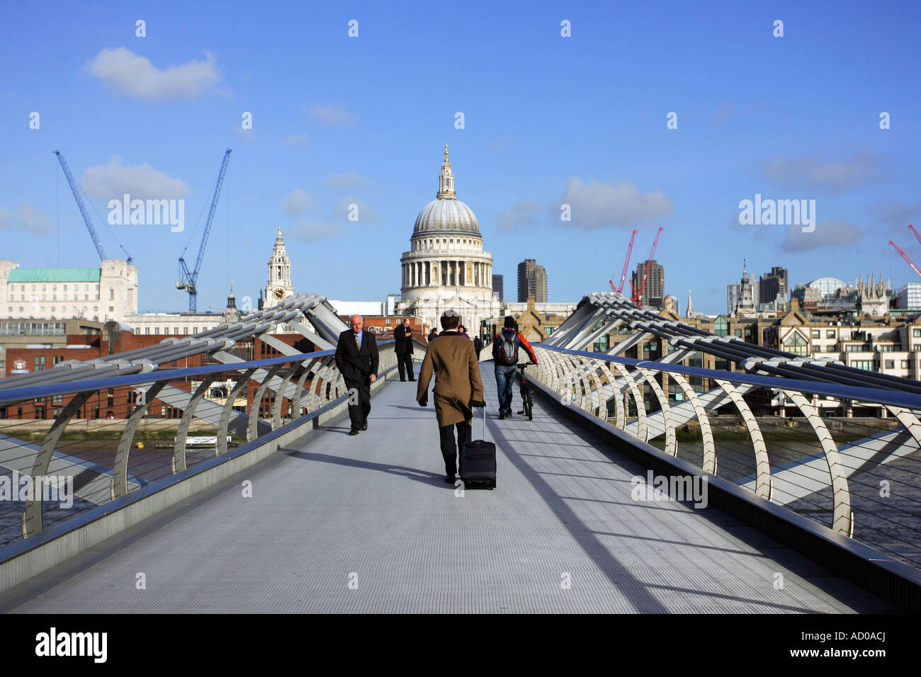 People walk over the Millenium Bridge towards St Pauls Cathedral London ...