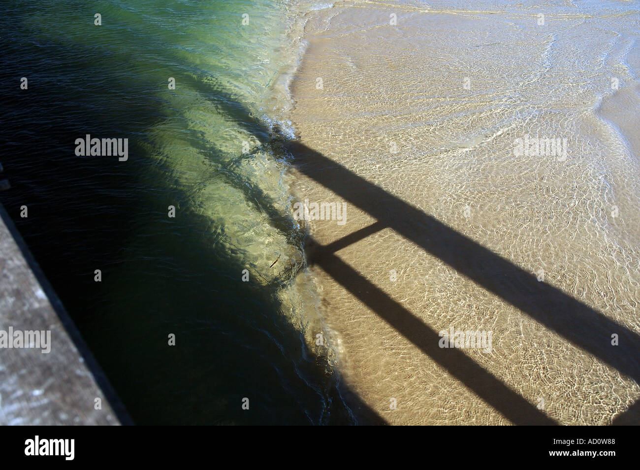 Shadow of jetty on shallow green seawater Stock Photo - Alamy