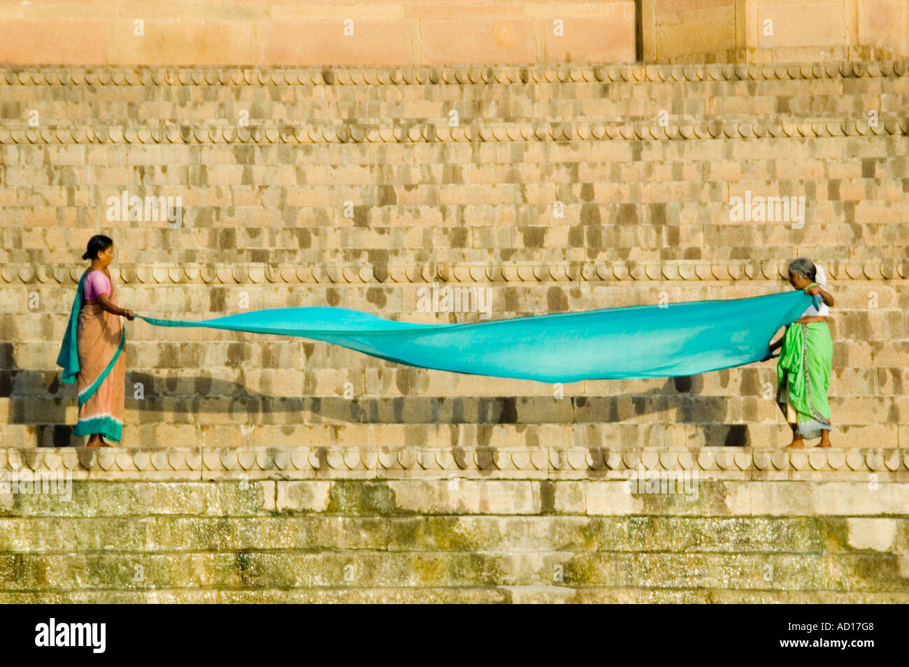 Horizontal view of two Indian women 'dhobi wallahs' laying out a long ...