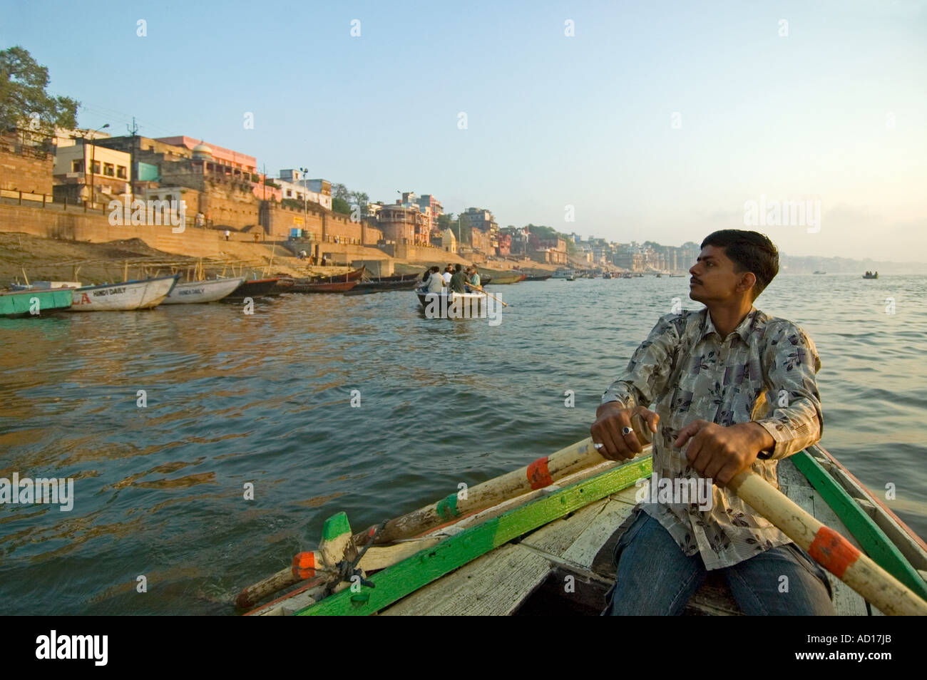 Horizontal wide angle of an Indian boy rowing up the River Ganges on a ...