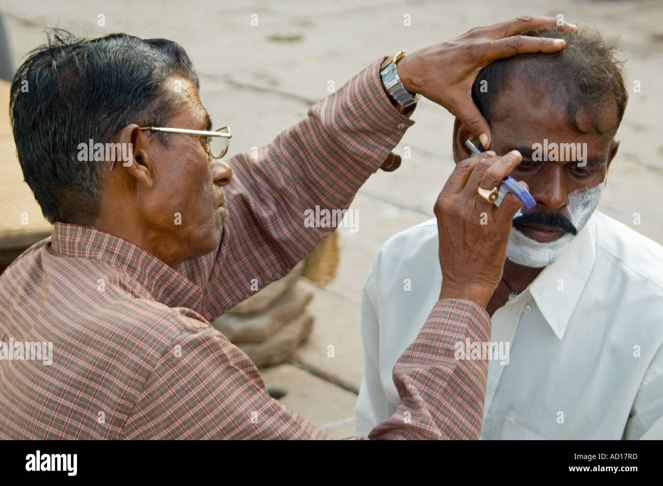 Horizontal close up of an Indian man having a shave outside on the ...