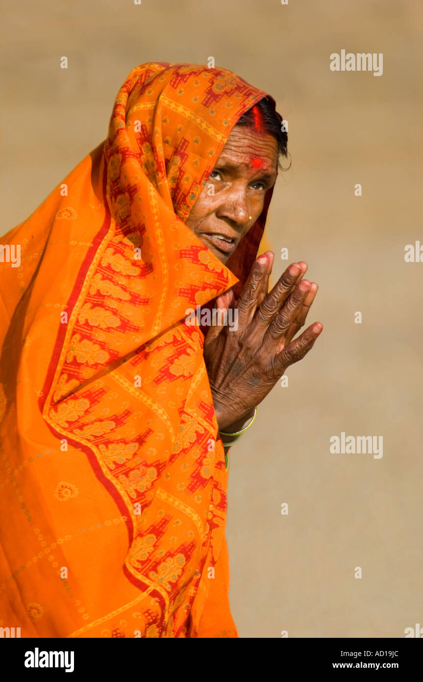 An elderly Indian woman wearing an orange coloured shawl and bindi mark ...