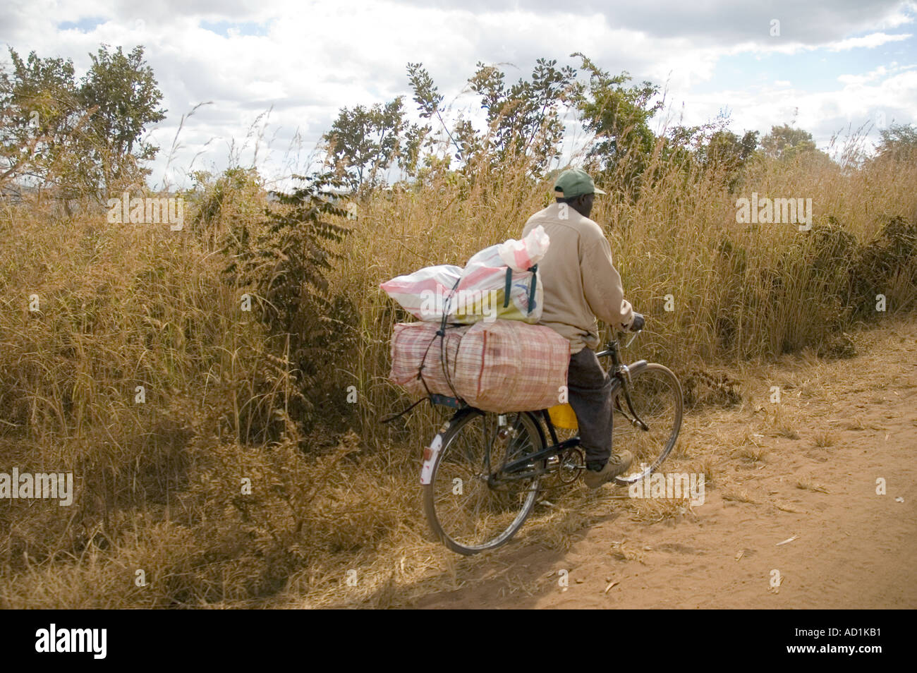 African man carrying load on his bicycle as a taxi or lorry service in ...