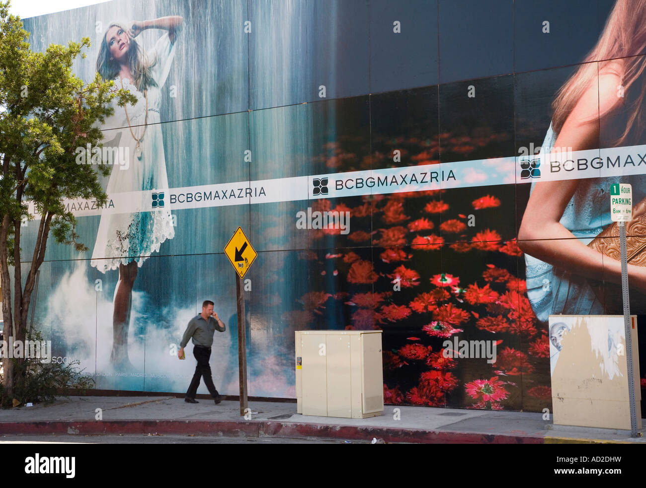 A man with a cell phone walks in front of a wall with a mural ...