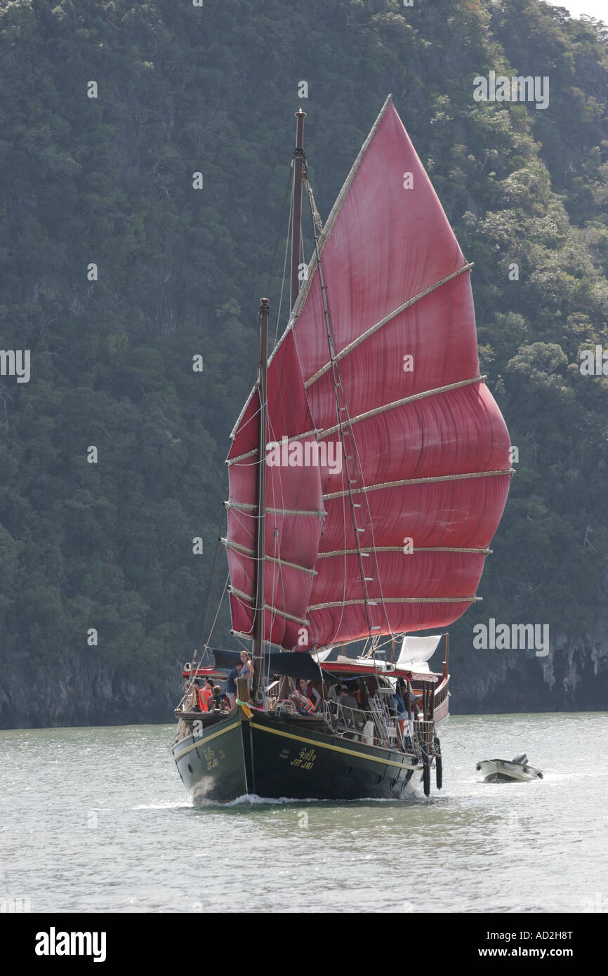 Head-on view of a traditional wooden Thai sailing junk against a wooded ...