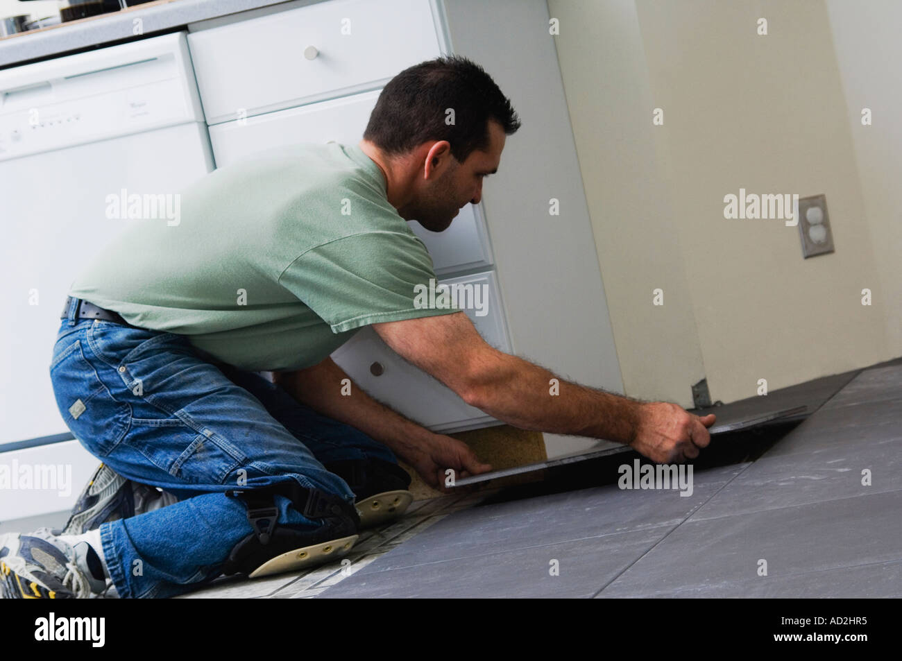 Construction worker laying tile floor Stock Photo - Alamy