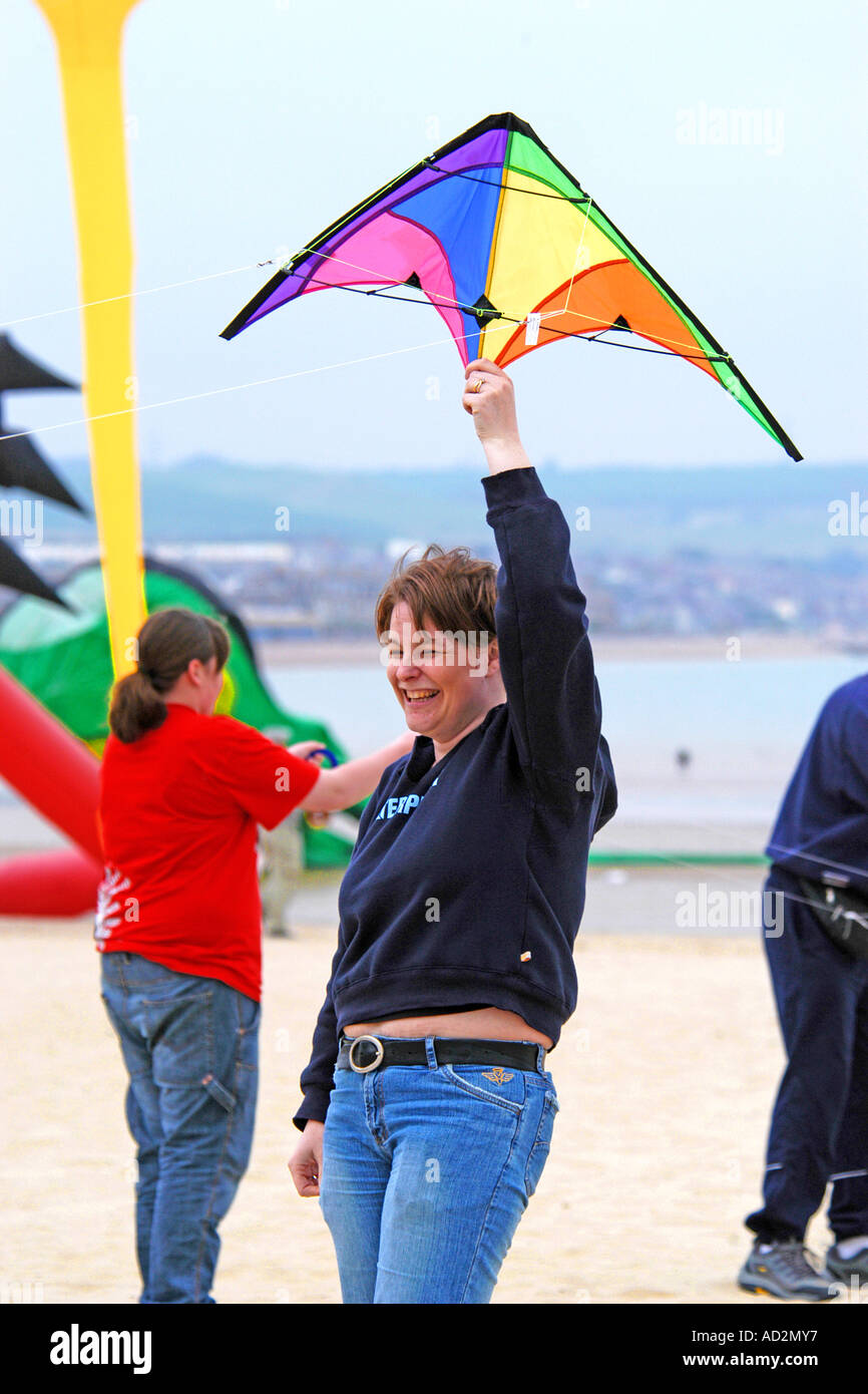 An adult Female launching a kite from a windy beach Stock Photo - Alamy
