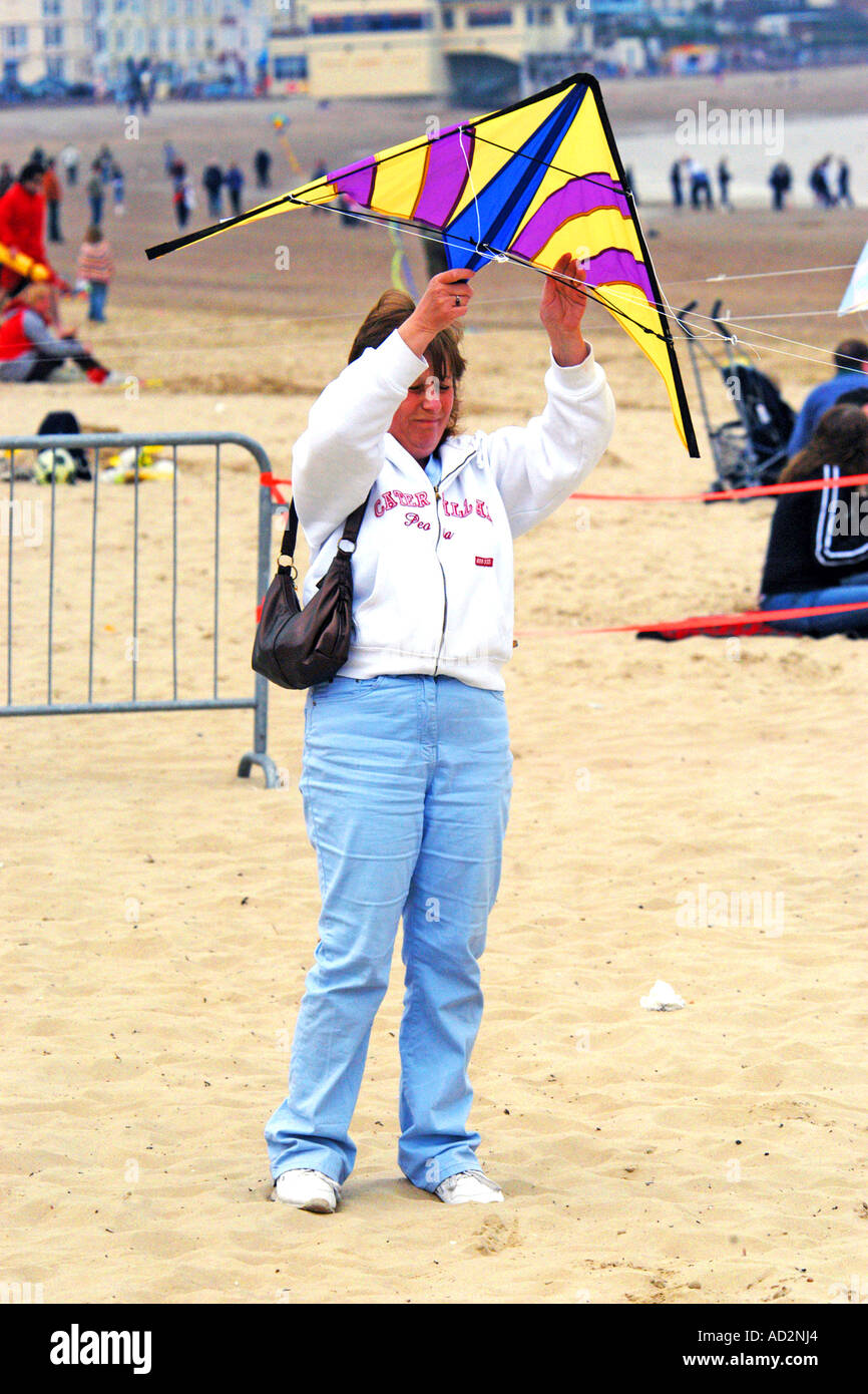 An adult Female launching a kite from a windy beach Stock Photo - Alamy