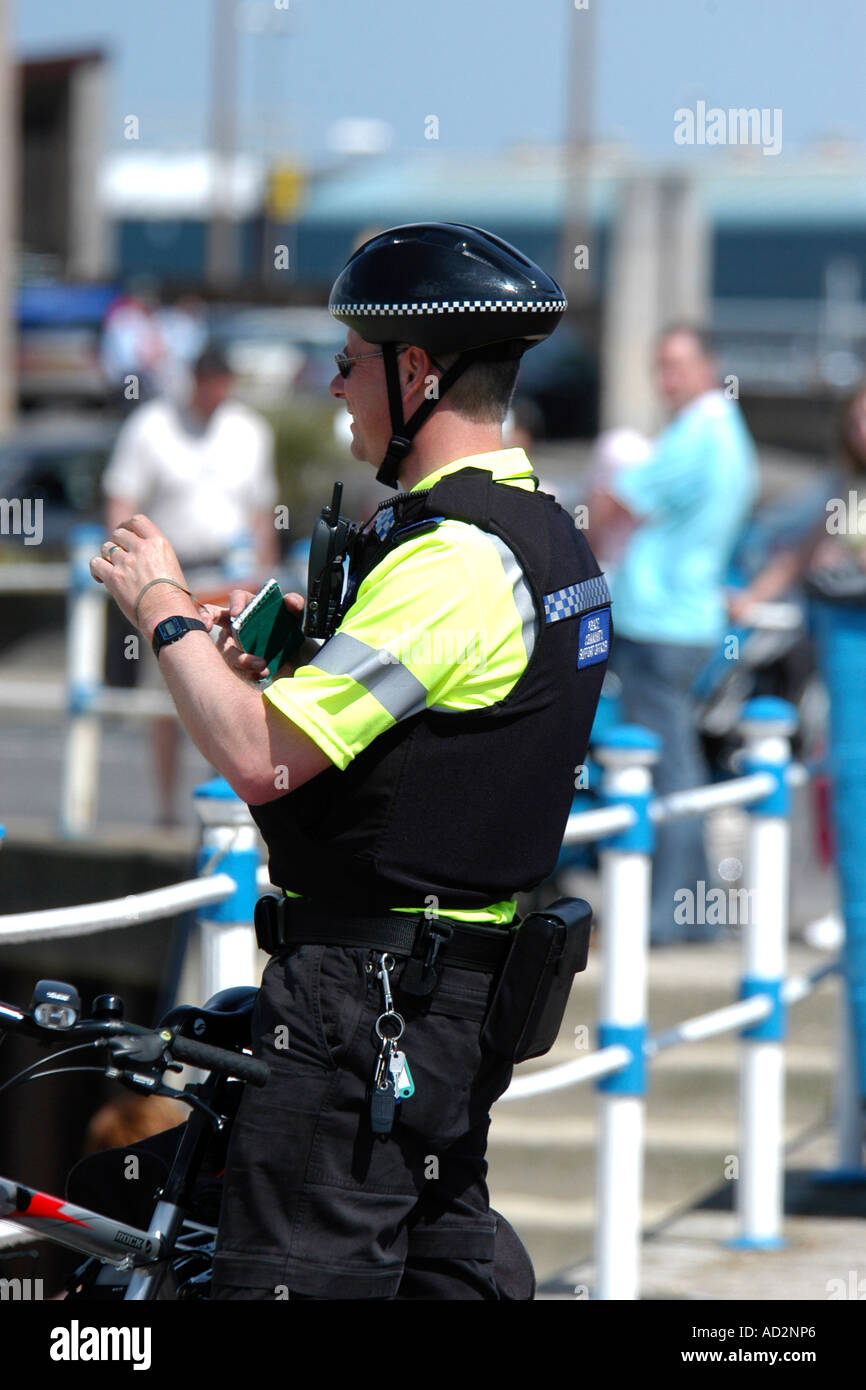 British bicycle Patrol Policeman wearing a yellow vest and safety ...