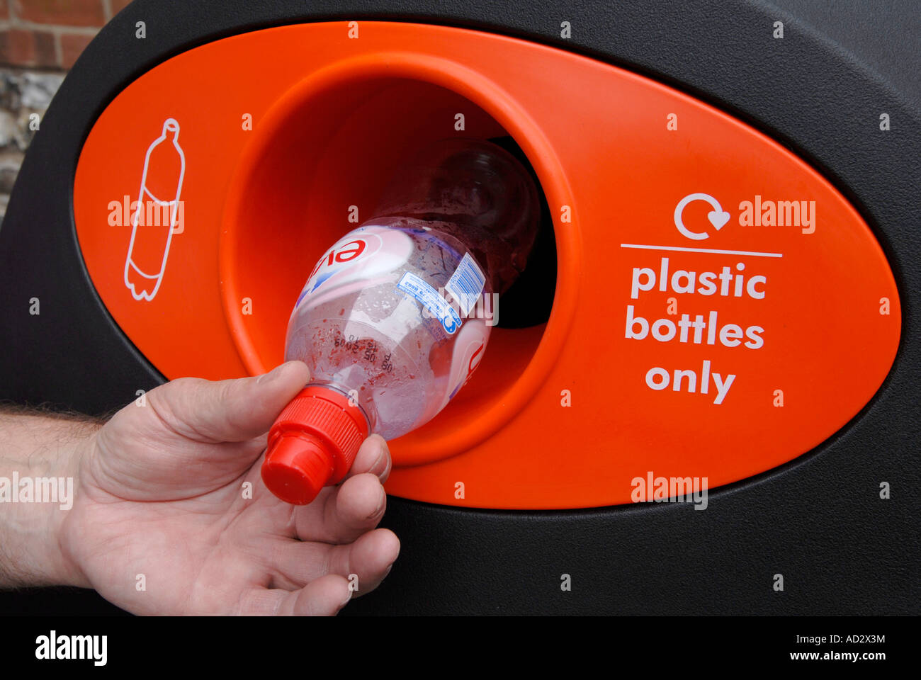 Man placing a plastic bottle for recycling in a local authority ...