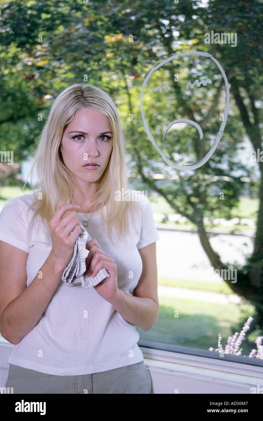 woman 20-40 cleaning window and drew a sad face to reflect her mood ...
