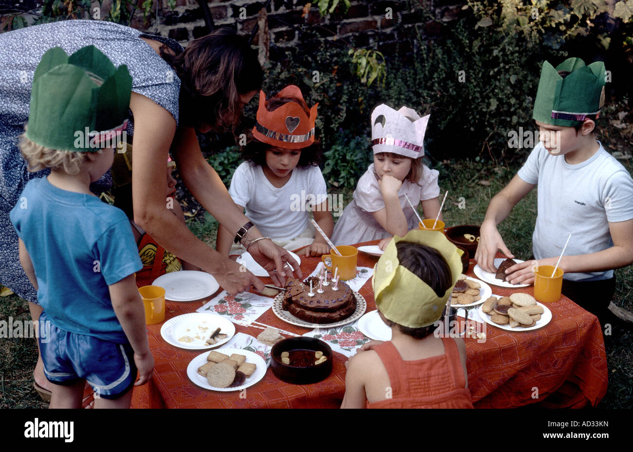 Children gathered around a table eating Birthday cake at a party Stock ...