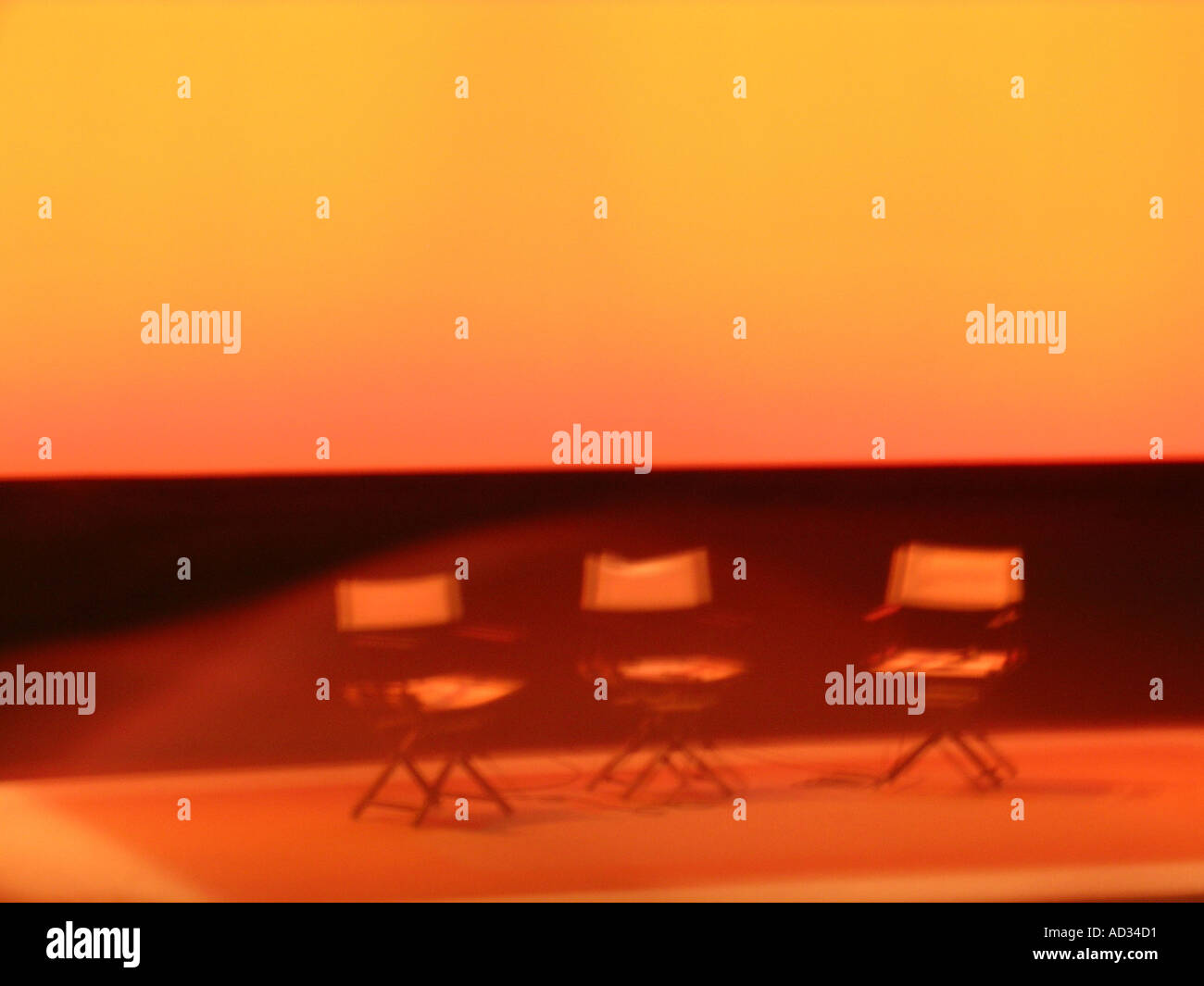 three empty chairs in a row on stage with large screen in background ...