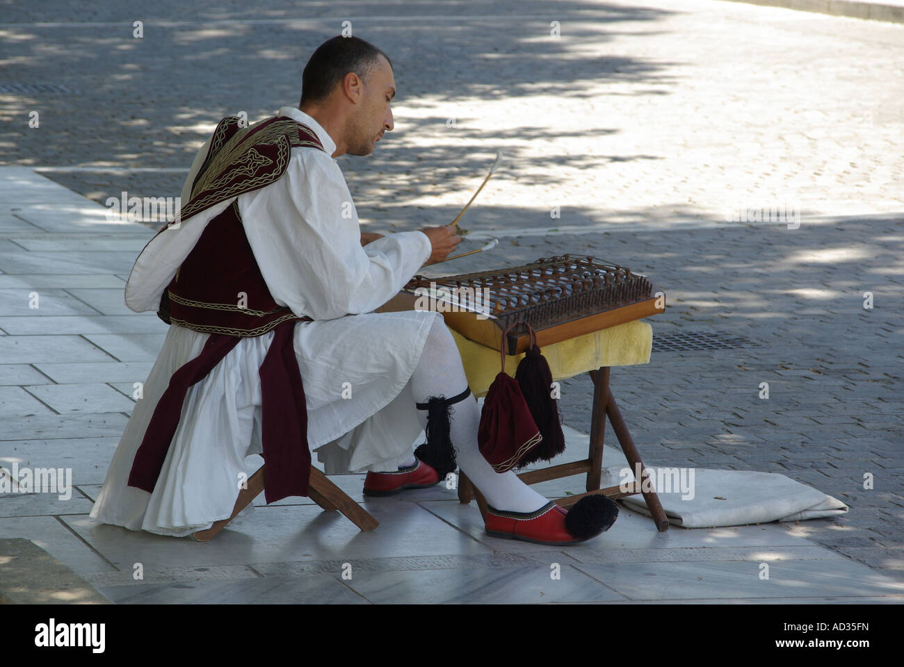 Athens man busking and playing musical instrument sitting on pavement ...