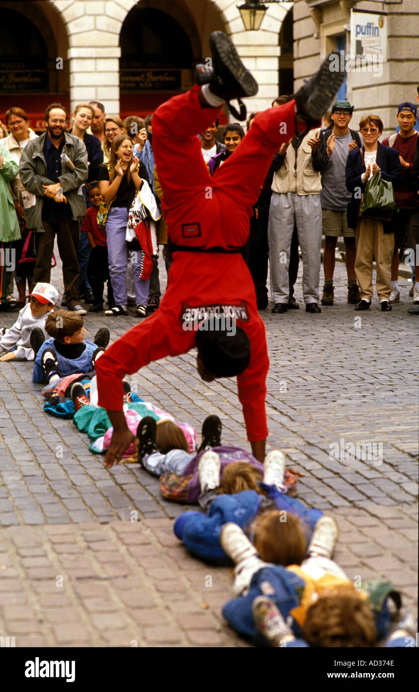 Busker at Covent garden walking on his hands over a line of children ...