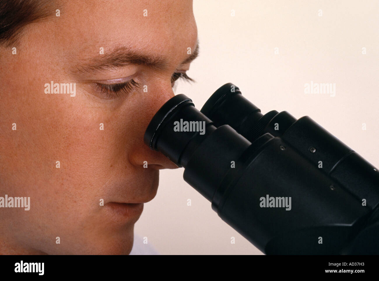 Close up of a male scientist looking into a microscope Stock Photo - Alamy