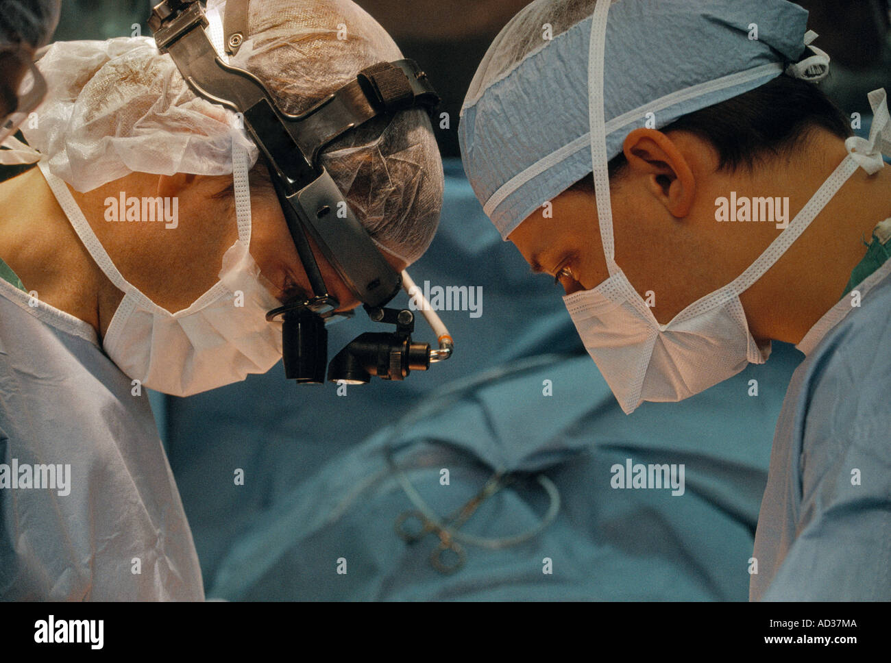 Two surgeons wearing scrubs and masks perform surgery in an operating ...