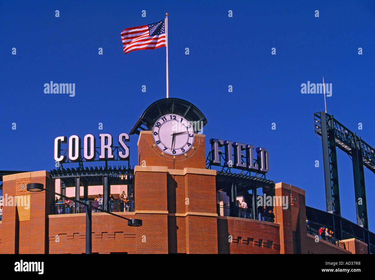 Flag flies over the clock and sign on the front of Coors Field, home of ...