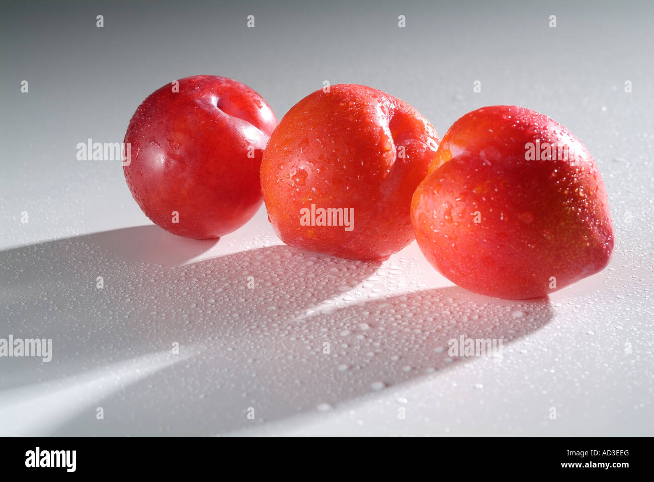 Three plums over white background Stock Photo - Alamy