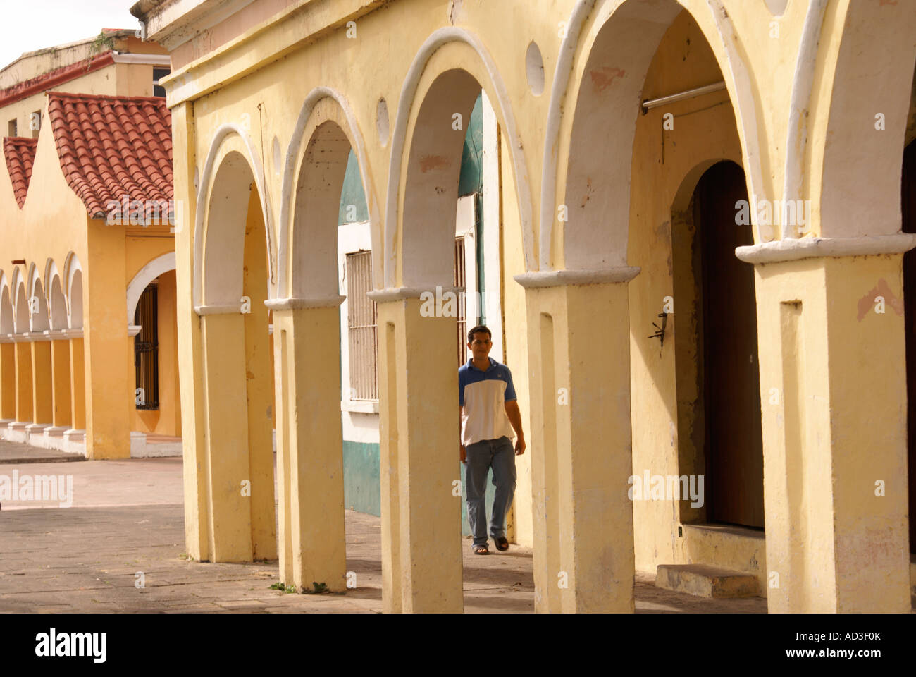 Man walking under an arcade in the Spanish colonial town of Tlacotalpan ...