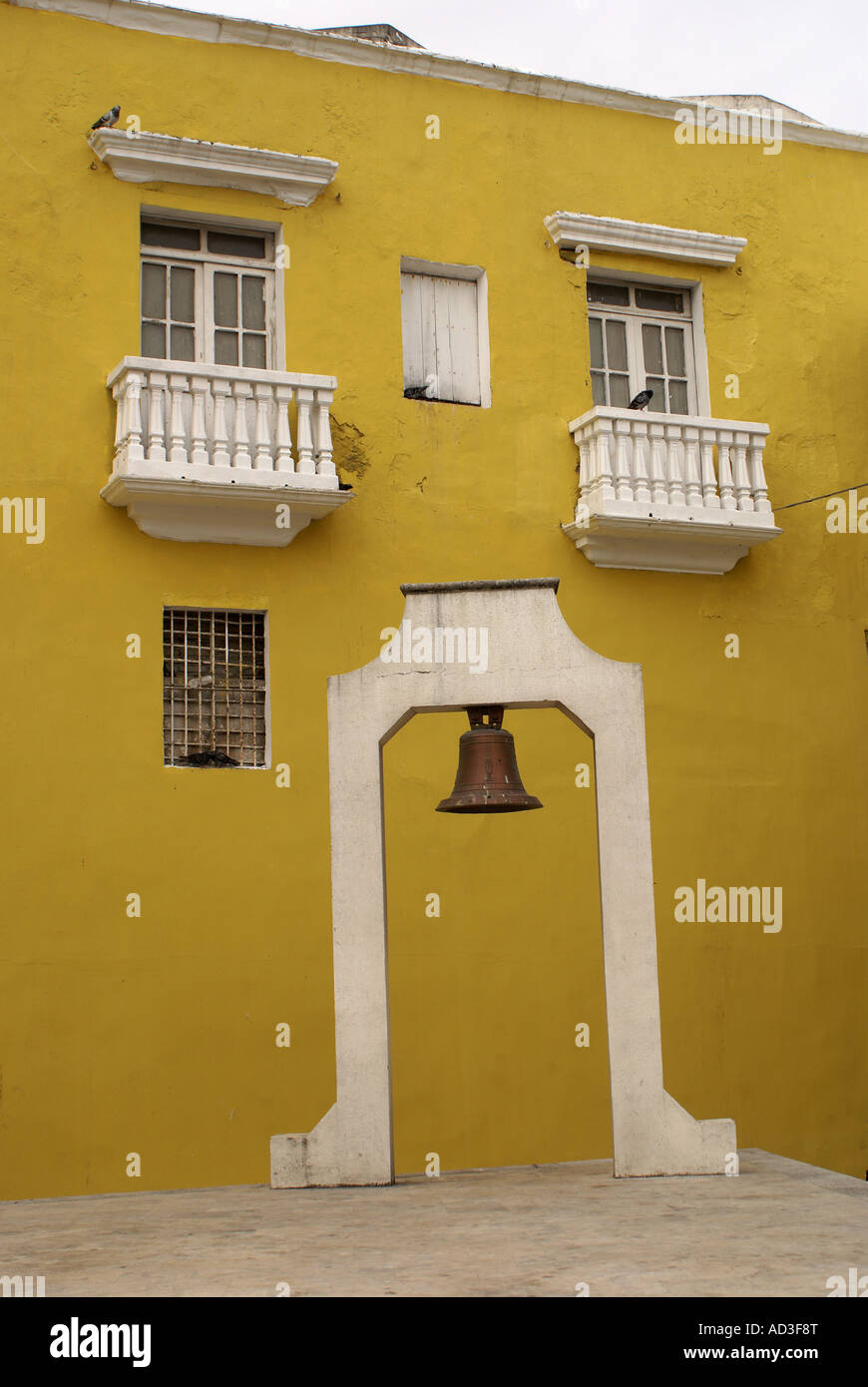 Old bell in front to of restored Spanish colonial buildings in the city ...
