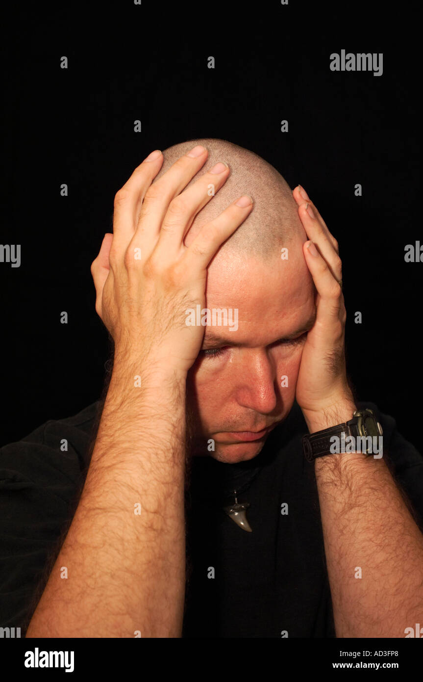A sad man with shaved head in a black shirt with black background Stock ...