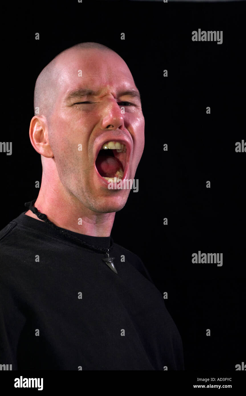 A man with a shaved head screaming in anger Stock Photo - Alamy