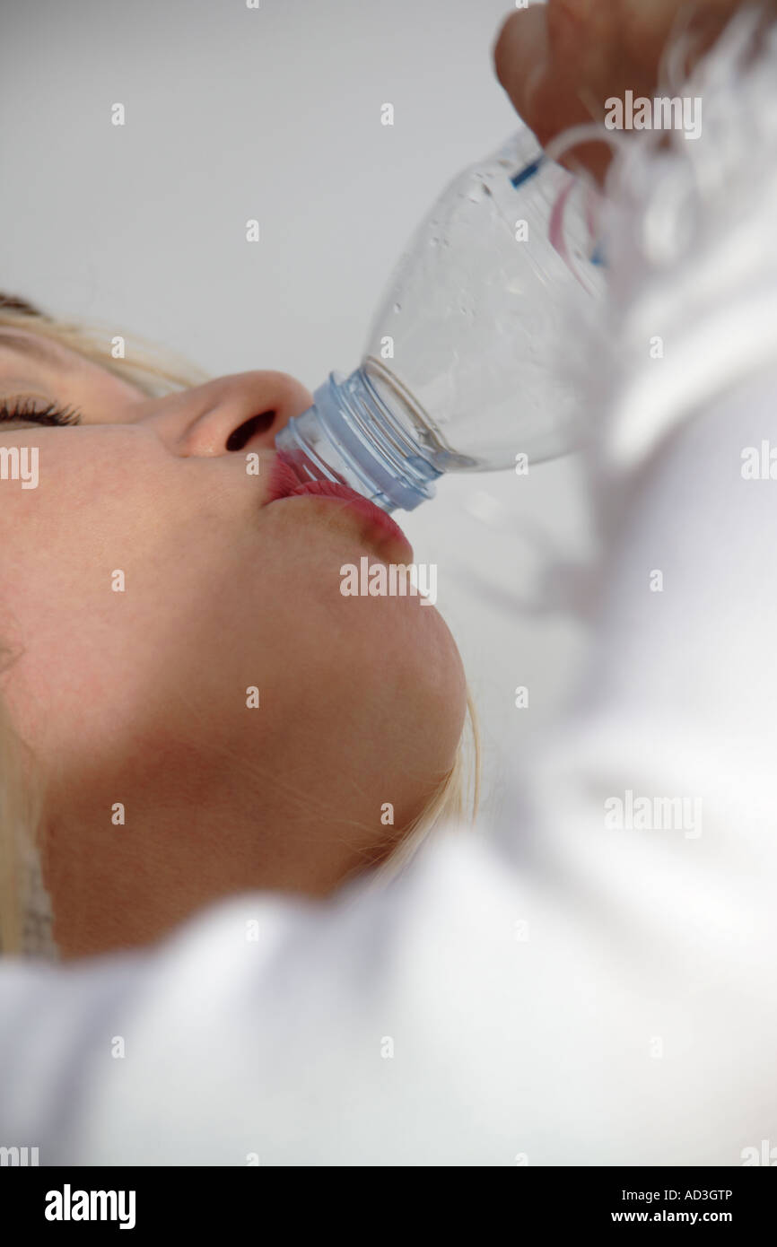 Woman drinking water from plastic bottle, low angle view, close up ...