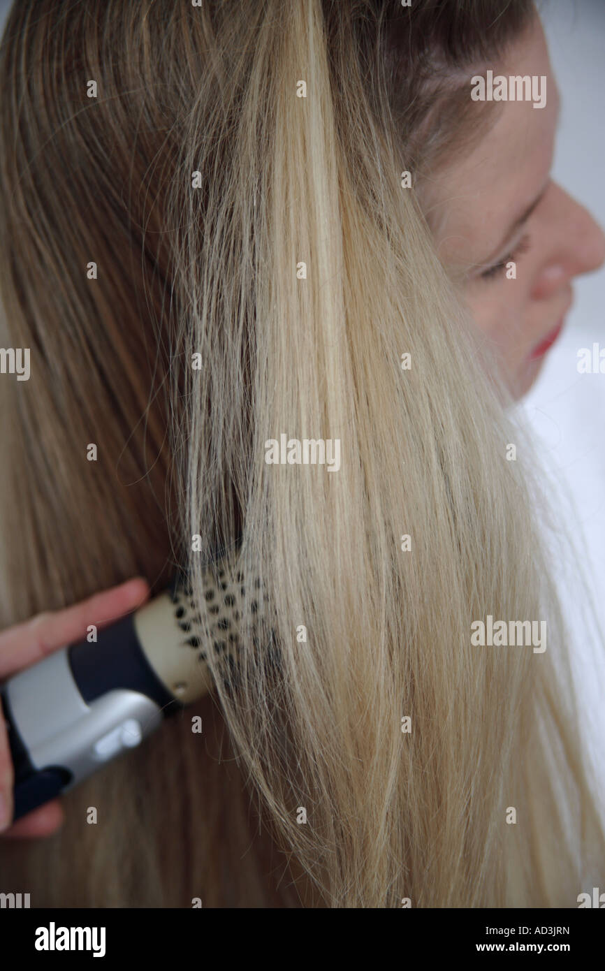 Woman with long blond hair using curling tongs Stock Photo - Alamy