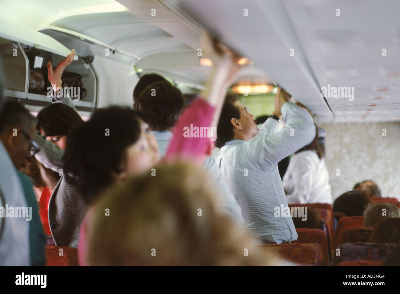 Air passengers placing or removing carry on luggage from overhead ...